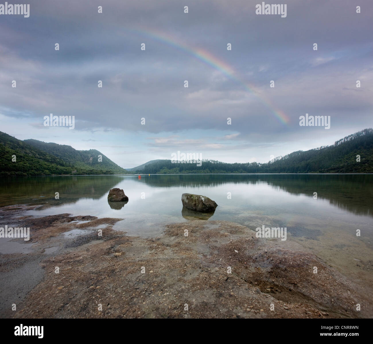 Rainbow stretching over rocky beach Stock Photo - Alamy