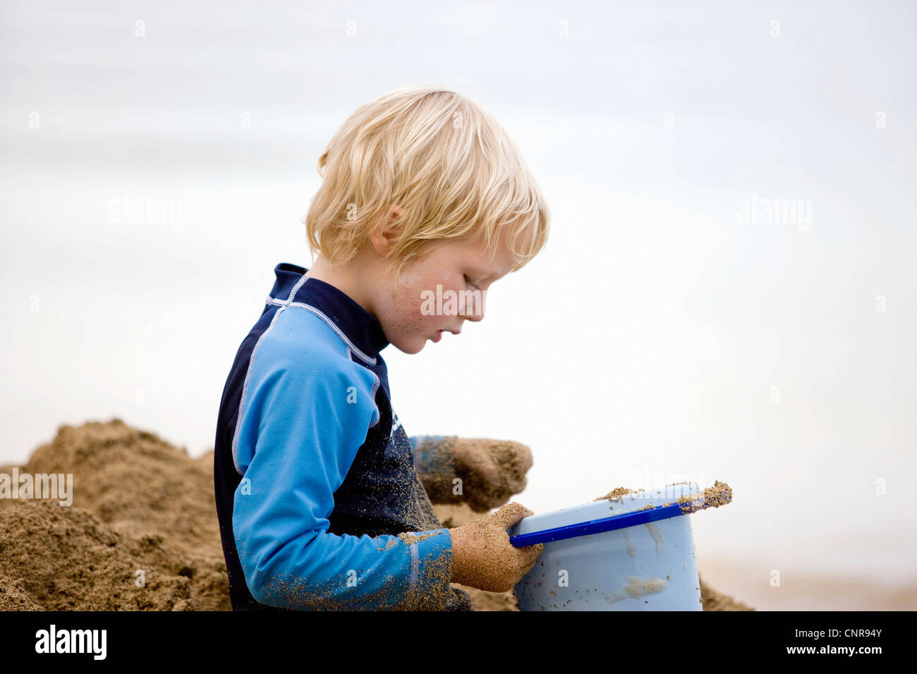 Boy playing with sand on beach Stock Photo - Alamy