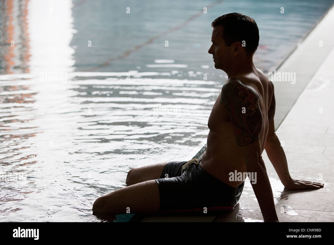 Man dangling legs in swimming pool Stock Photo - Alamy