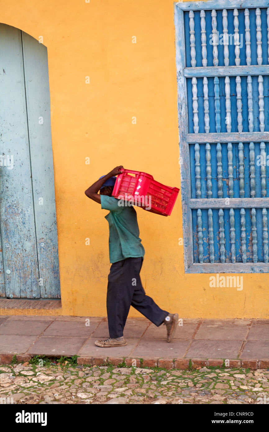 Daily life in Cuba - man walking down street past colourful buildings ...
