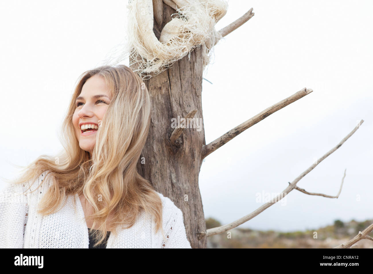 Smiling woman leaning against tree Stock Photo - Alamy