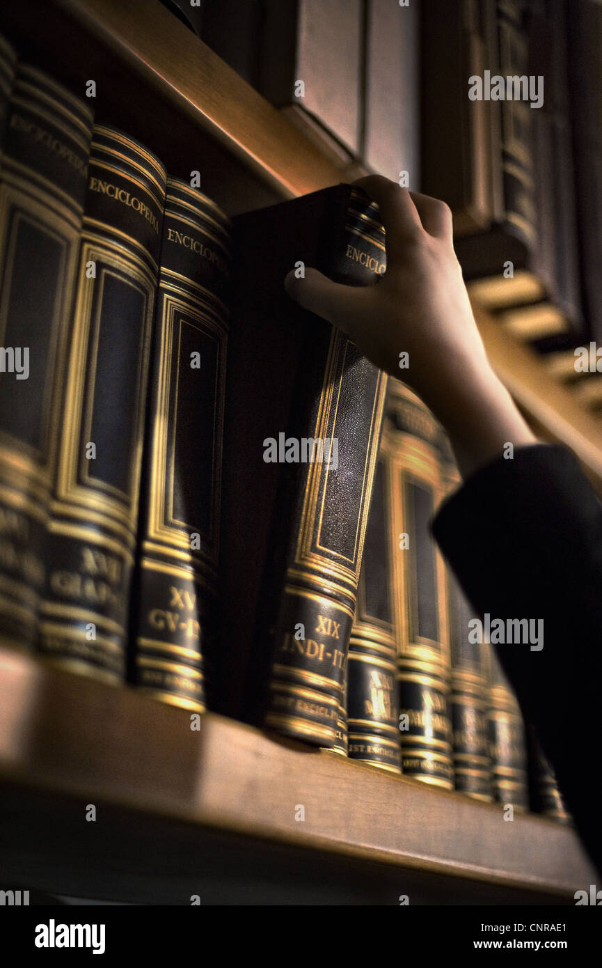 Hand pulling book from bookshelf Stock Photo - Alamy
