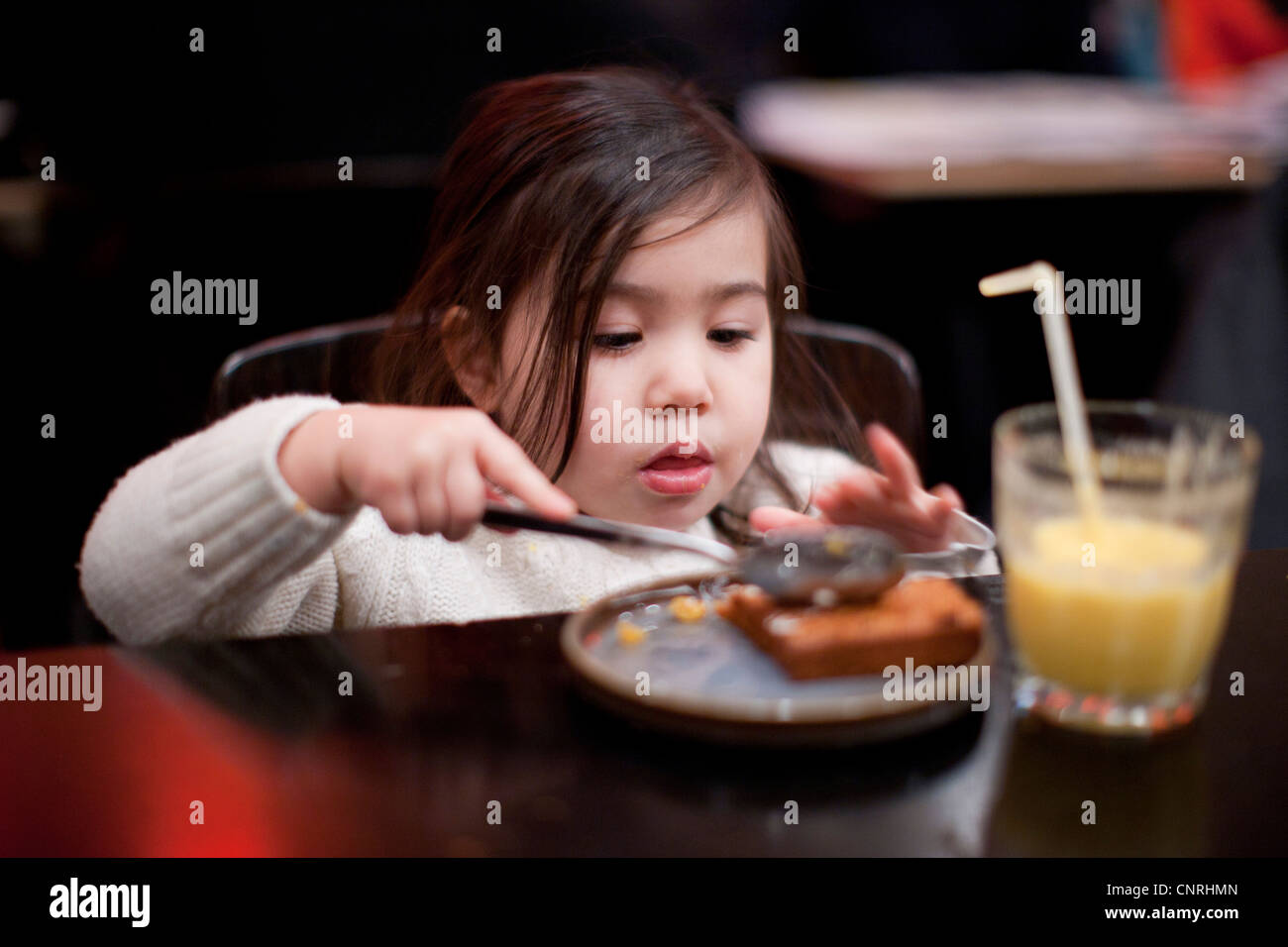 Little girl eating at table Stock Photo - Alamy