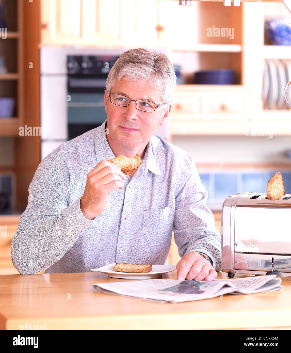 Middle aged man eating toast for breakfast in kitchen Stock Photo - Alamy