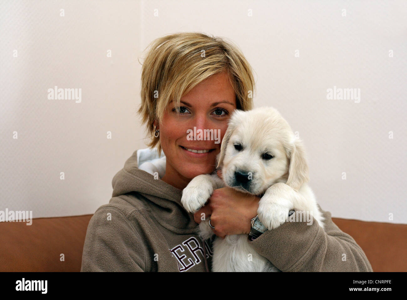 Golden Retriever (Canis lupus f. familiaris), young woman sitting on a ...