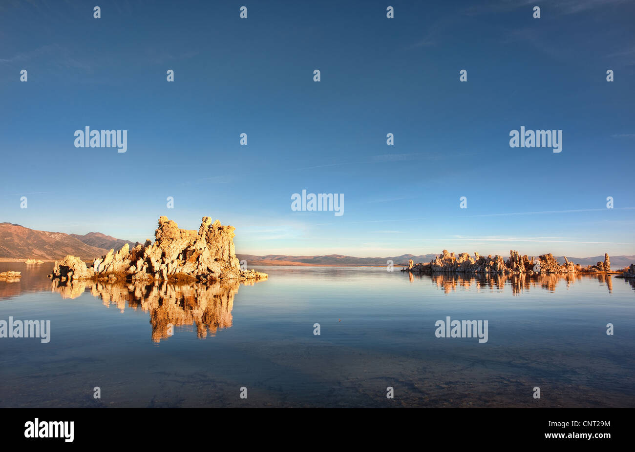 Exposed tufa rock formations reflected in the still waters of Mono Lake ...