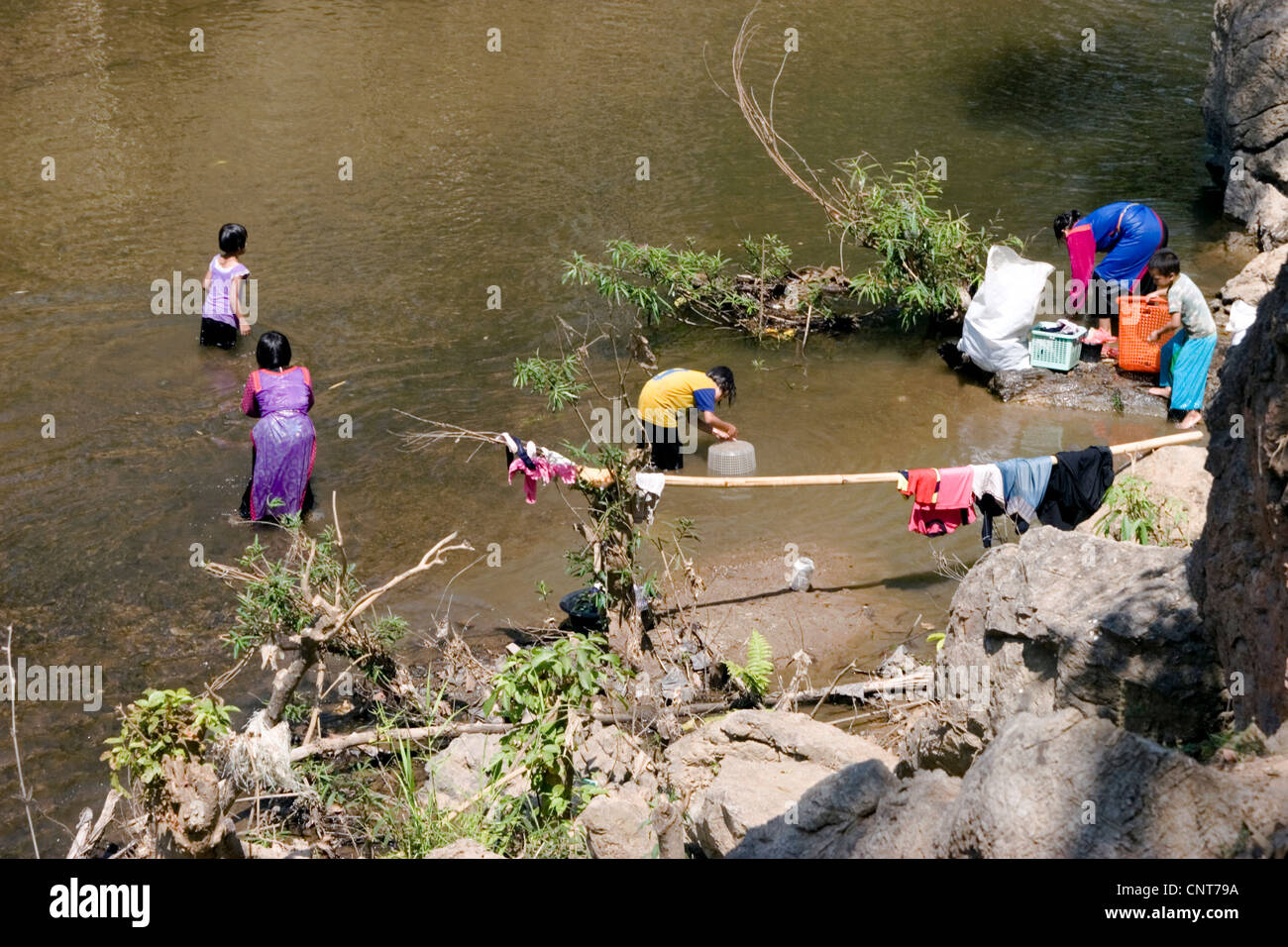 A family of hill tribe slash and burn farmers are washing clothes in a ...