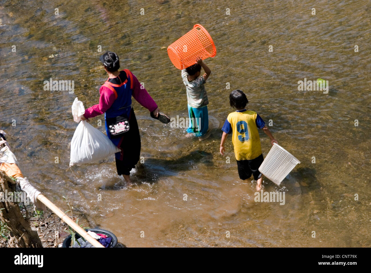 A family of hill tribe slash and burn farmers are washing clothes in a ...