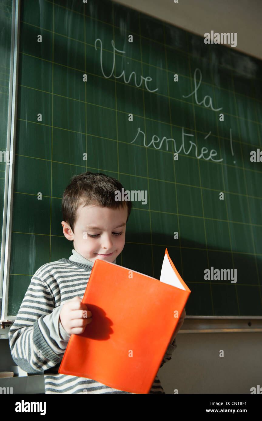 Boy reading in front of blackboard in classroom Stock Photo - Alamy