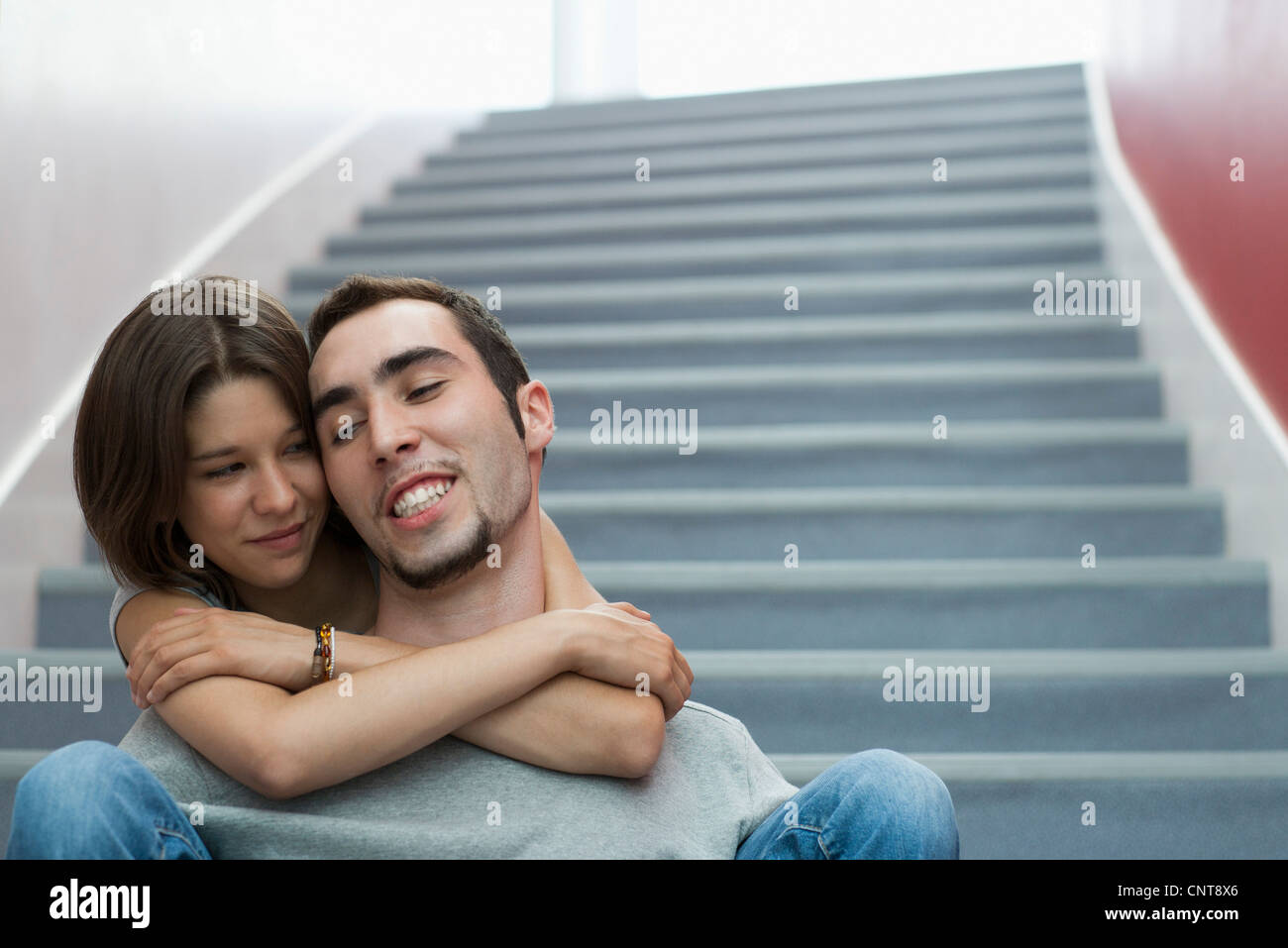 Young couple sitting on stairs, embracing Stock Photo - Alamy