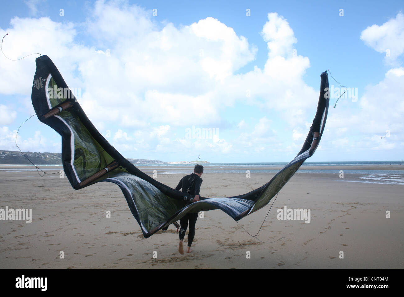 Kitesurfer carrying his kite to the sea on Hayle beach, Cornwall Stock ...
