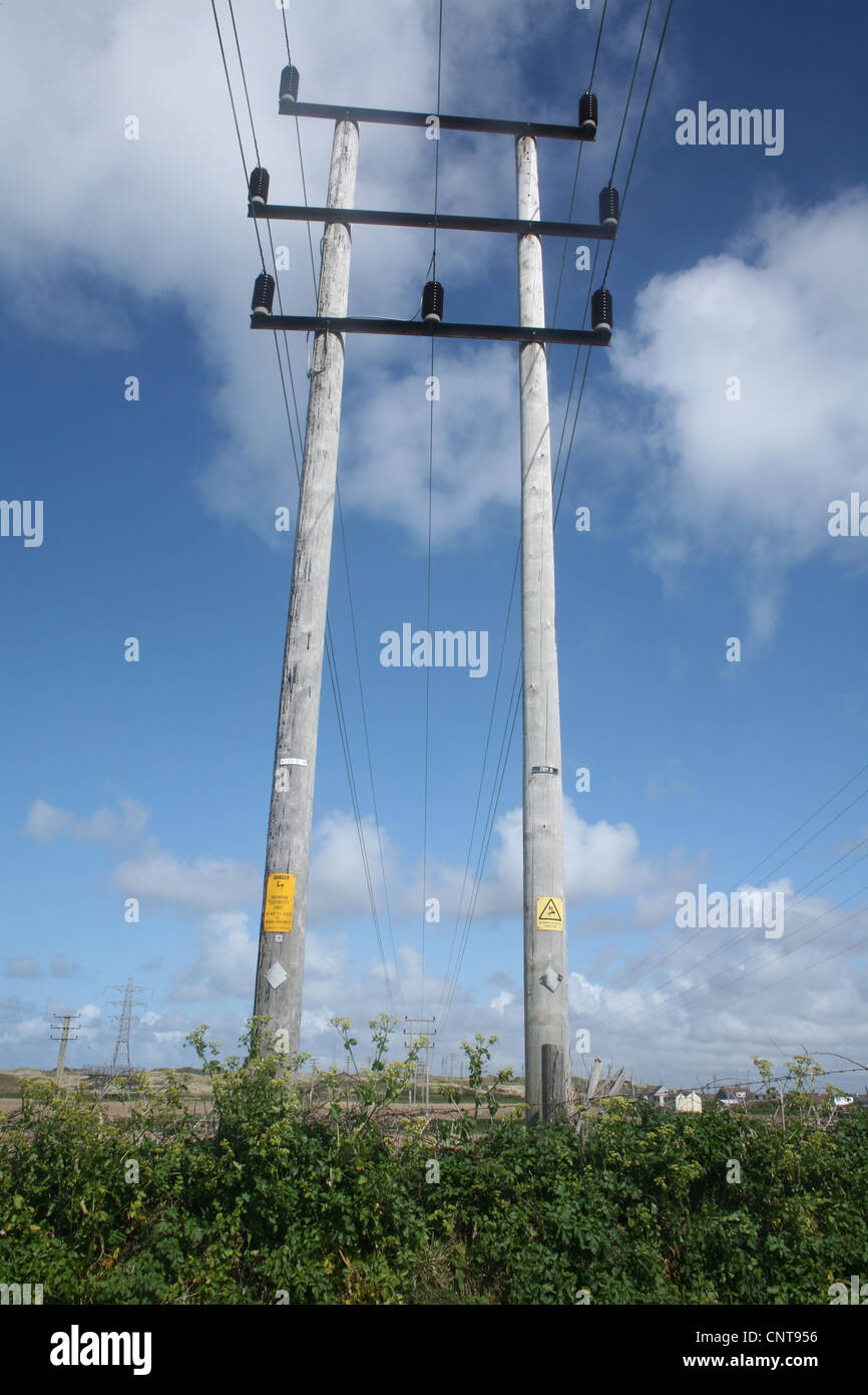 Electric Pylons with blue sky and green hedge Stock Photo - Alamy