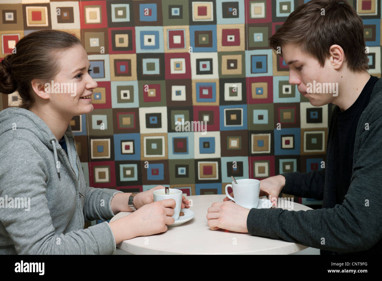 Two young people talking to each other at a café Stock Photo - Alamy