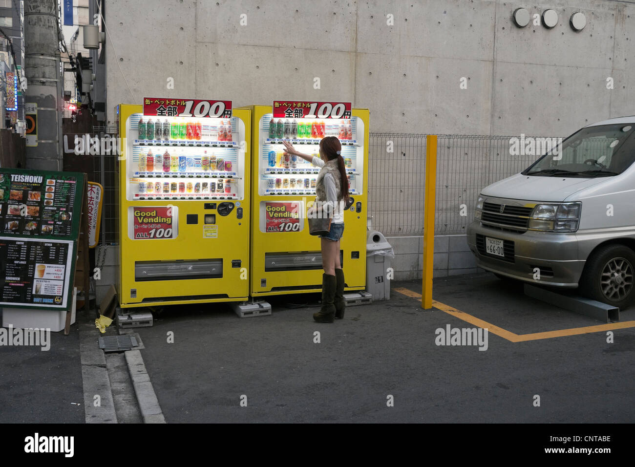 young Japanese woman buying a drink from a vending machine, Osaka ...