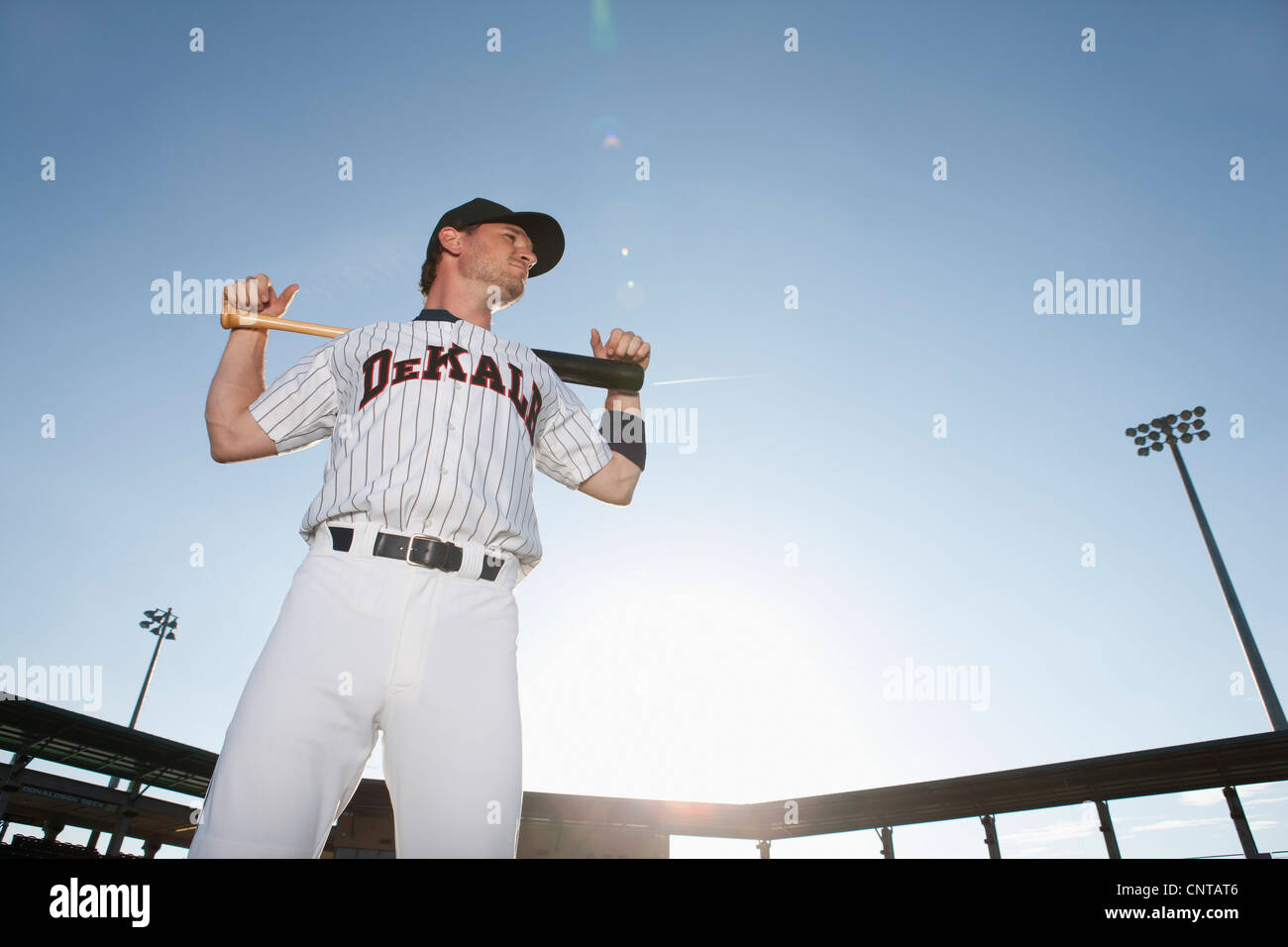 Baseball player holding bat across shoulders Stock Photo - Alamy