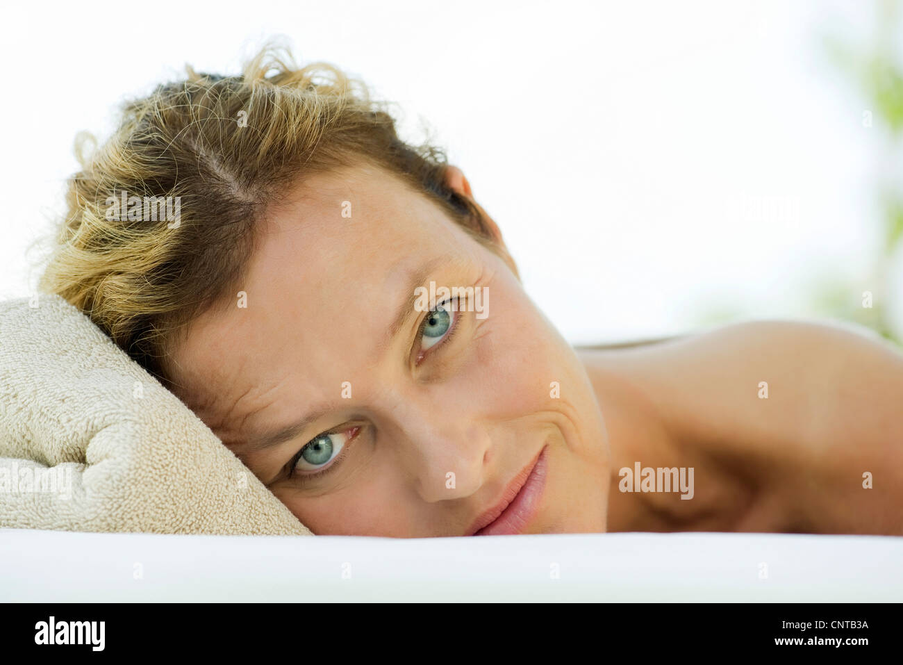 Woman lying down with head resting on towel, portrait Stock Photo - Alamy