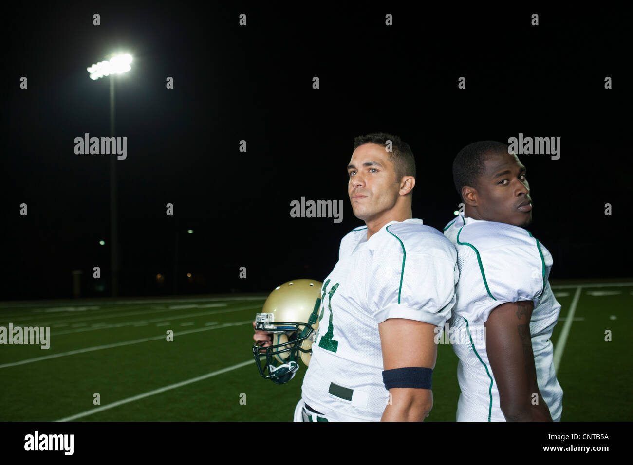 Football players standing back to back on field Stock Photo - Alamy