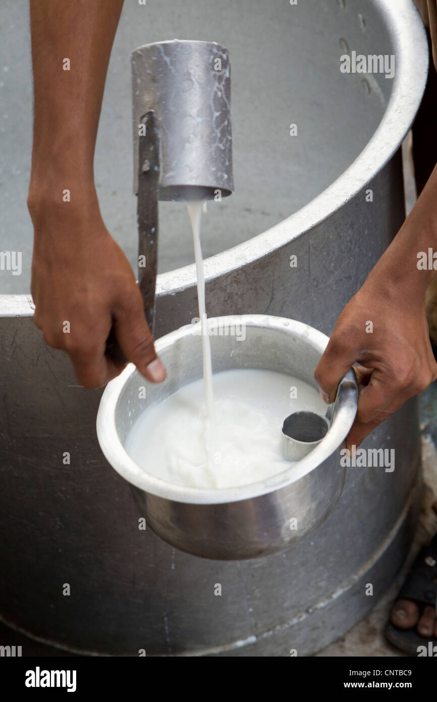 Man ladling fresh milk into pot, cropped Stock Photo - Alamy