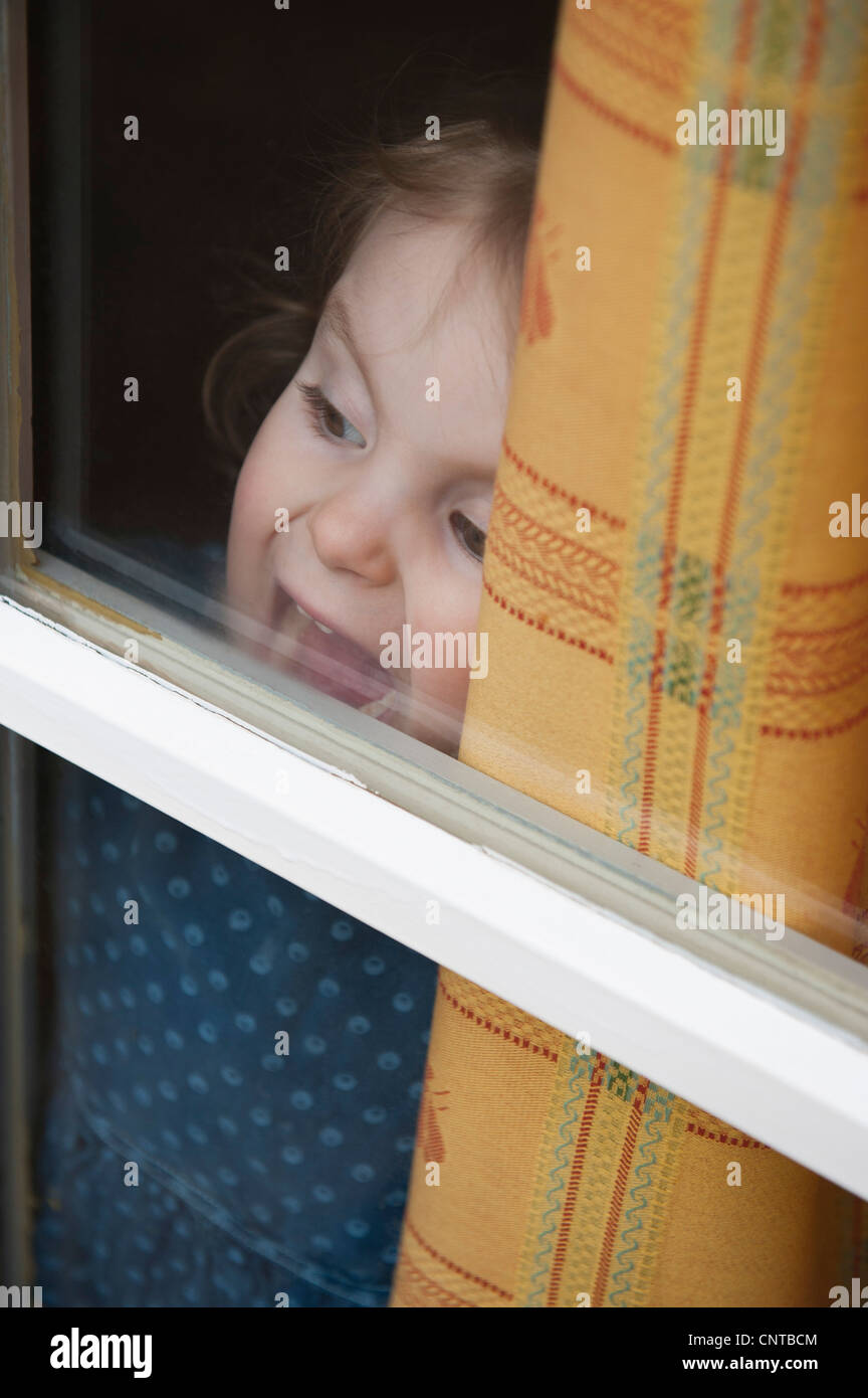 Little girl looking through window Stock Photo - Alamy