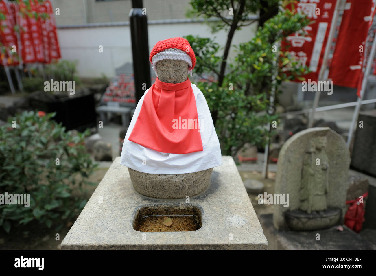 stone Jizo statue with bib and wool caps at Shitenno-Ji temple, Osaka ...