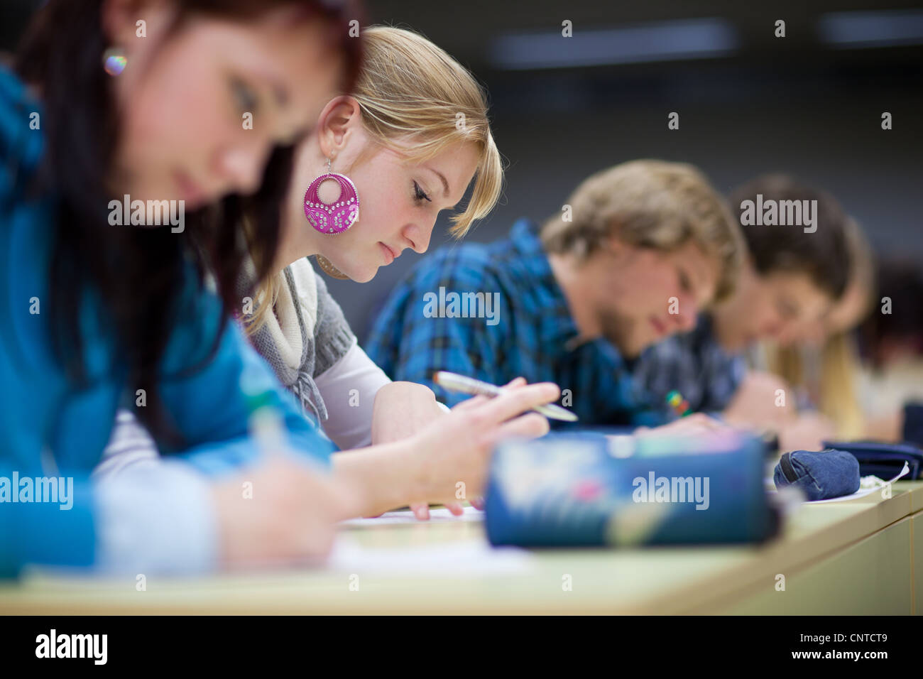 pretty female college student sitting in a classroom full of students ...