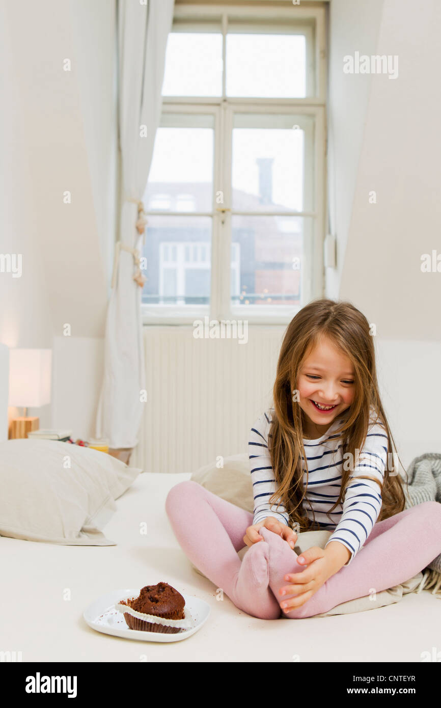 Girl eating chocolate muffin on bed Stock Photo - Alamy