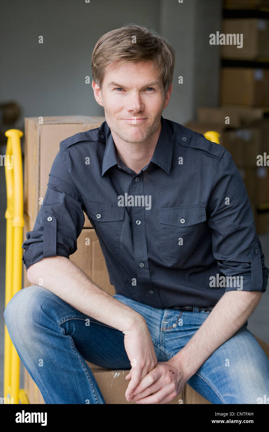 Smiling man sitting on boxes on dolly Stock Photo - Alamy