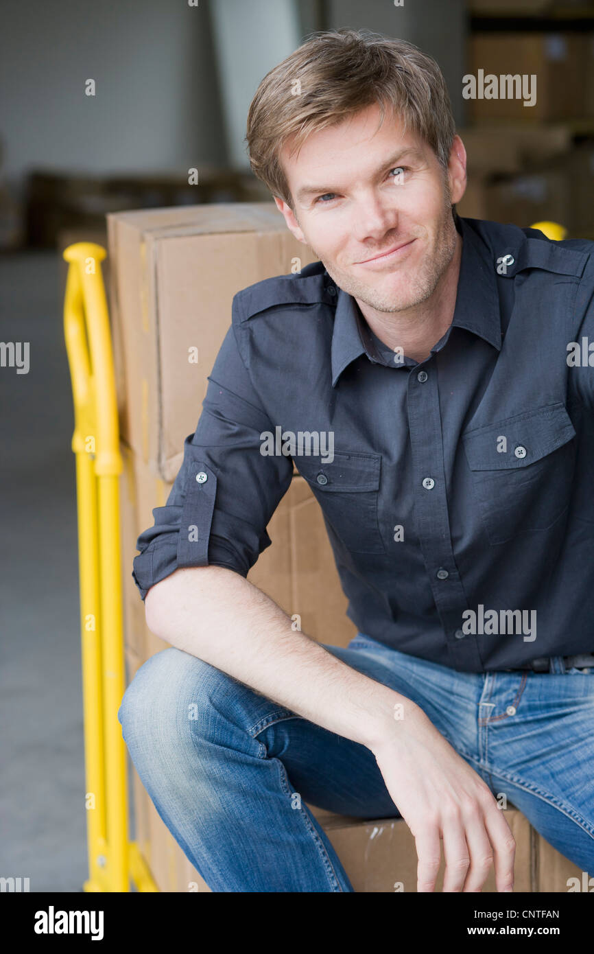 Smiling man sitting on boxes on dolly Stock Photo - Alamy