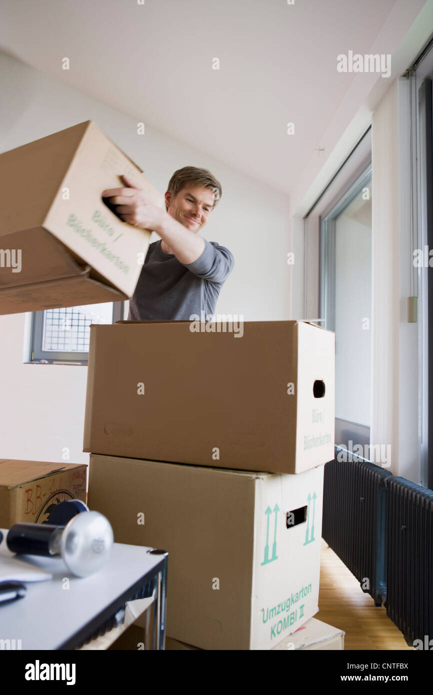 Man stacking cardboard boxes in house Stock Photo - Alamy