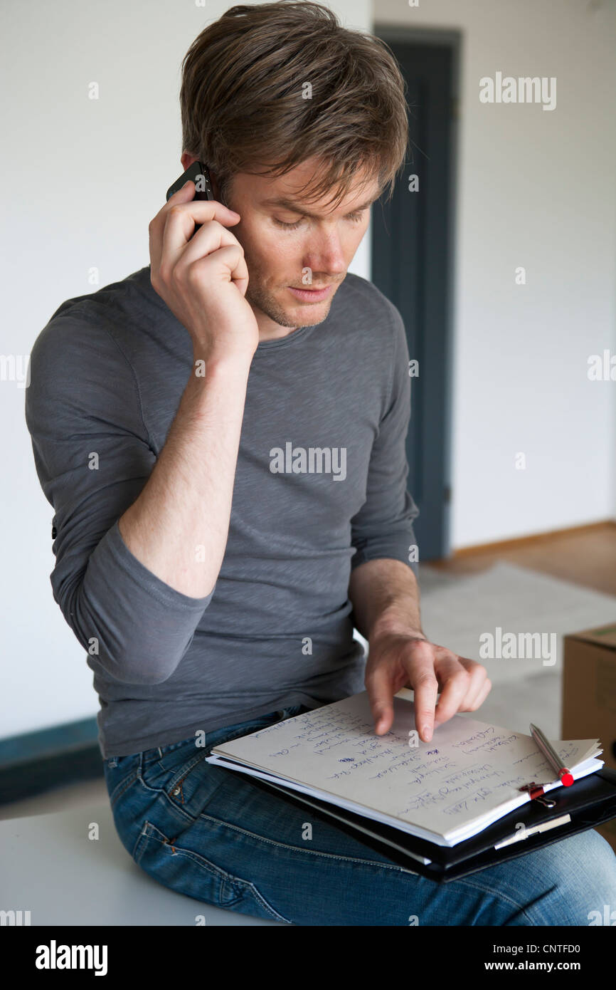 Man on cell phone taking notes Stock Photo - Alamy