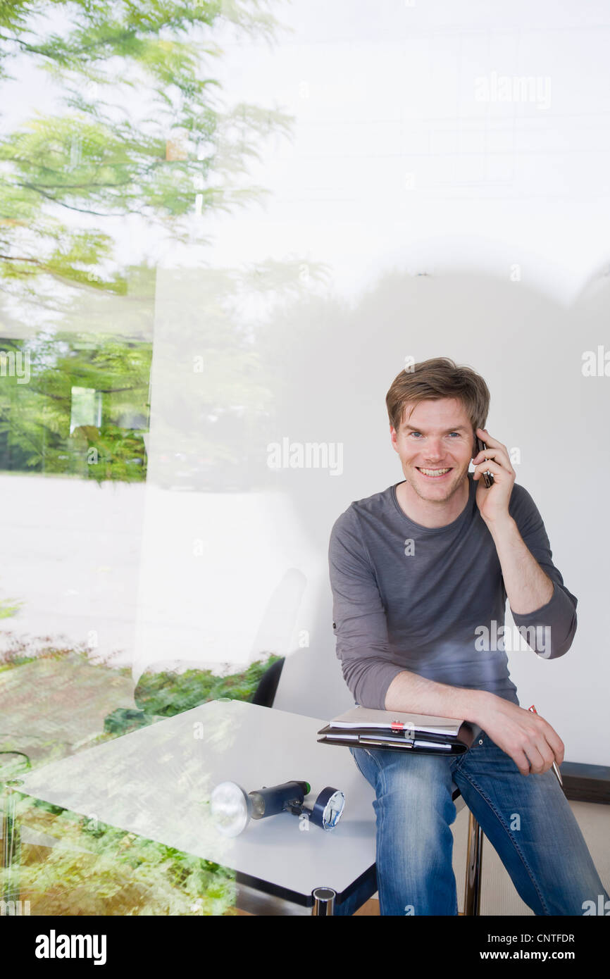 Man on cell phone taking notes Stock Photo - Alamy