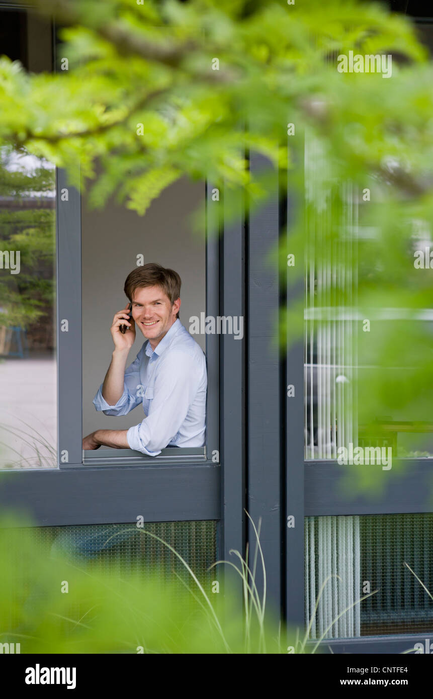 Businessman using cell phone in window Stock Photo - Alamy