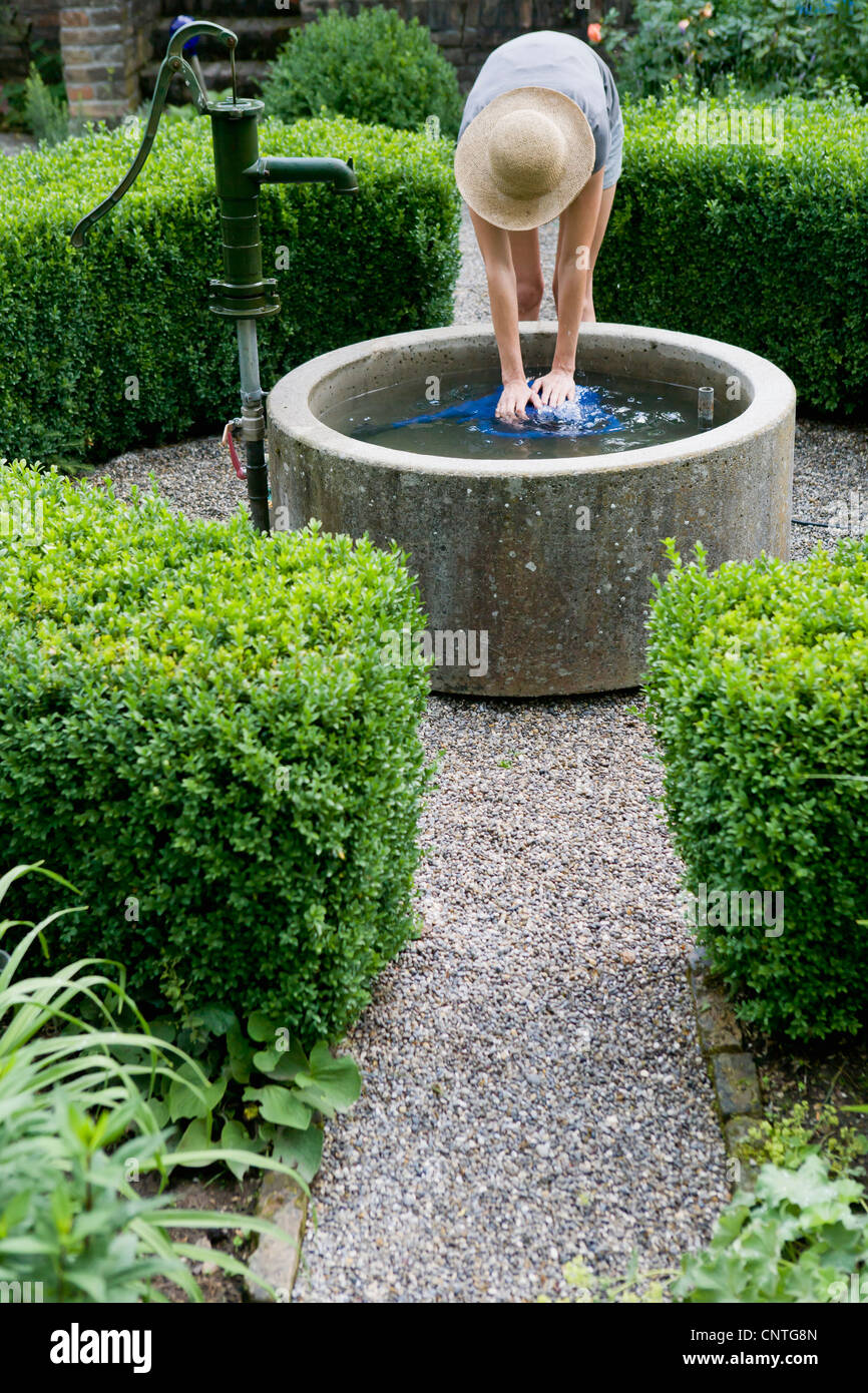 Woman filling watering can in pond Stock Photo - Alamy