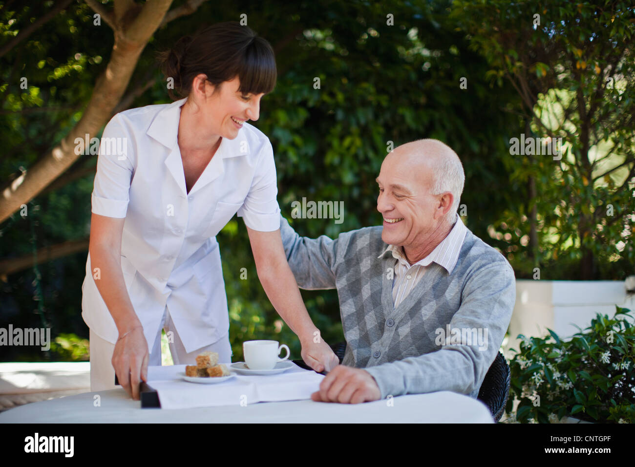 Waitress serving older man coffee Stock Photo - Alamy