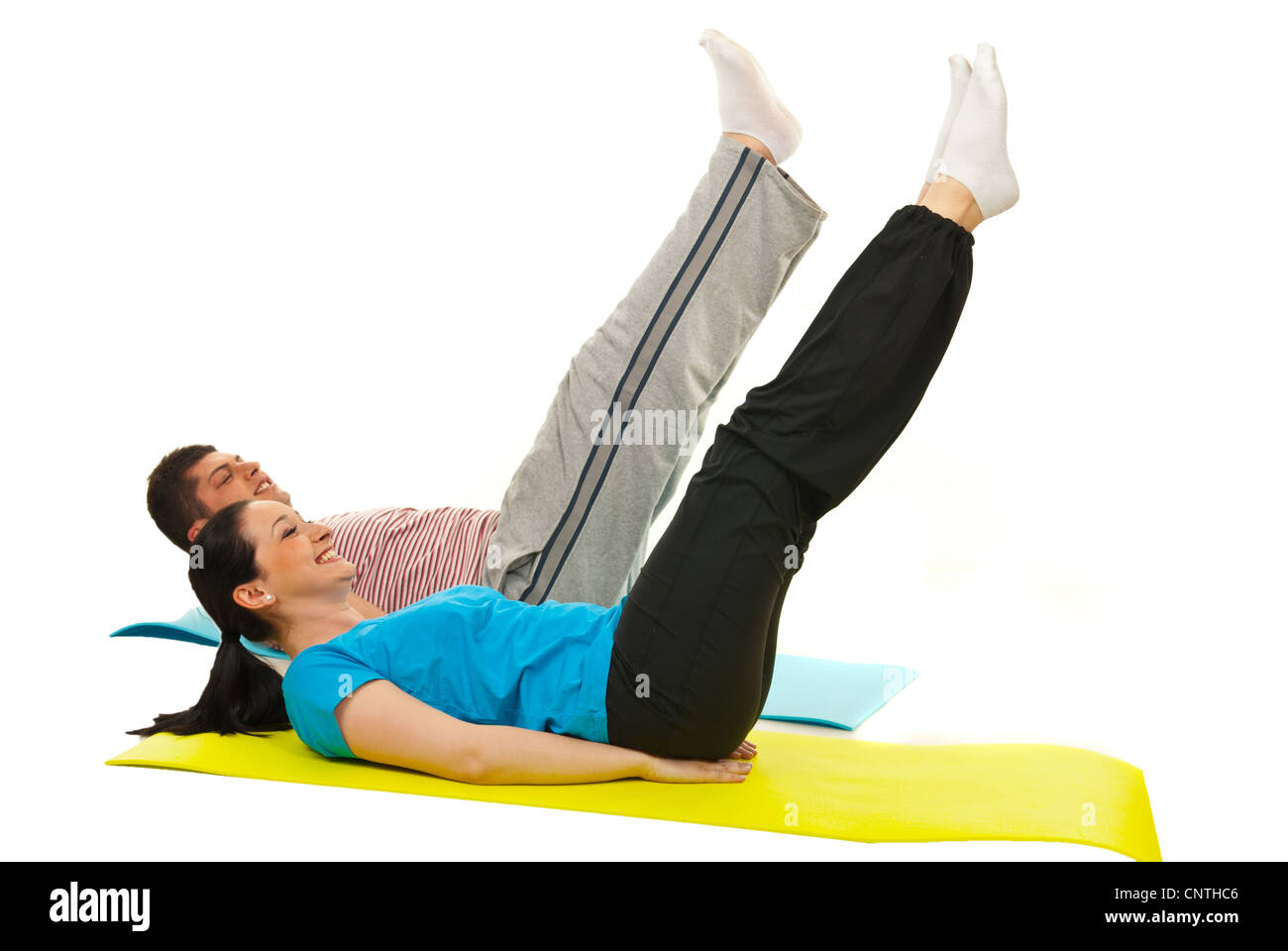 Happy couple doing sport and lying on gymnastic mats raising legs ...
