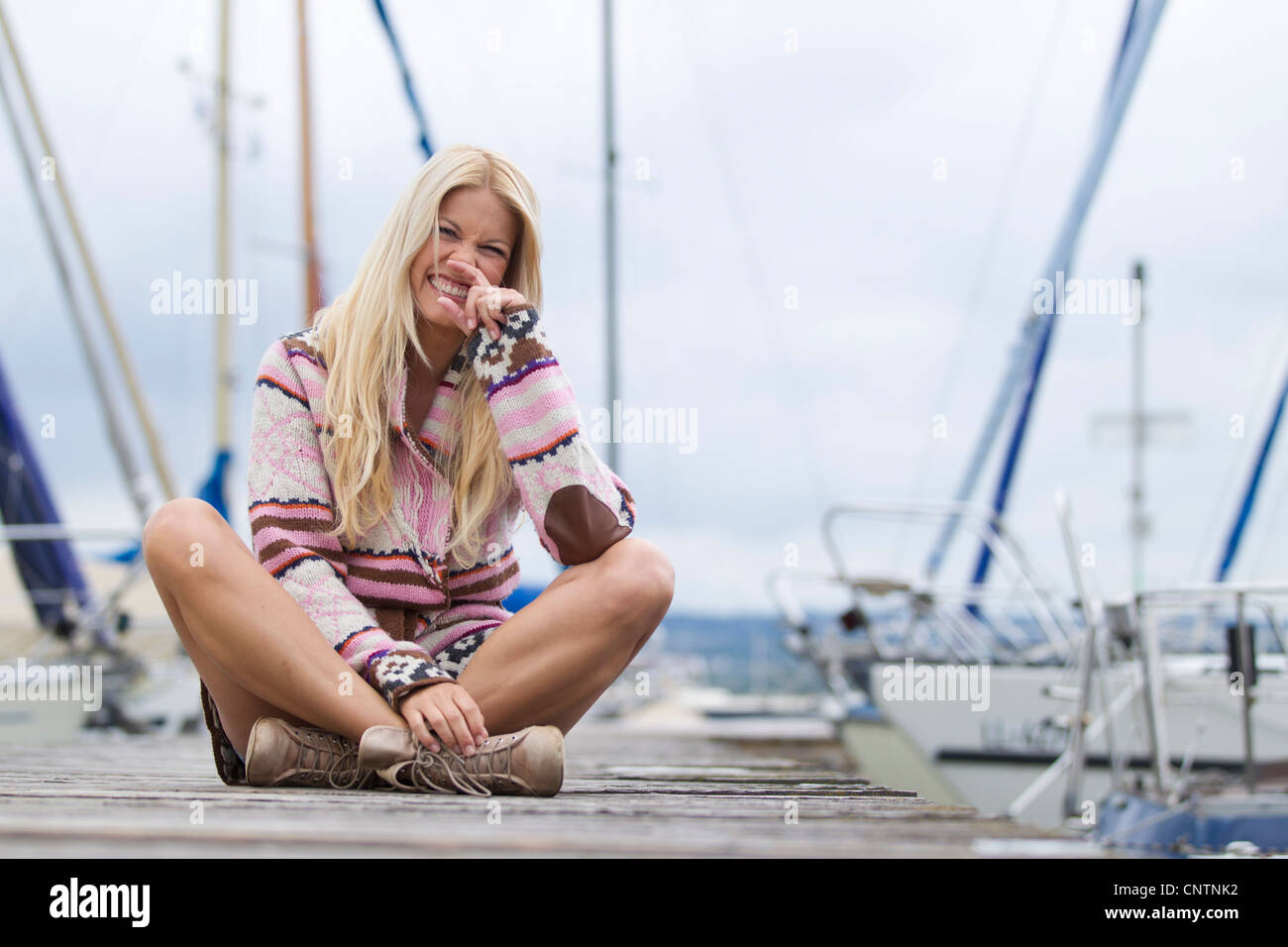Smiling woman sitting on wooden dock Stock Photo - Alamy