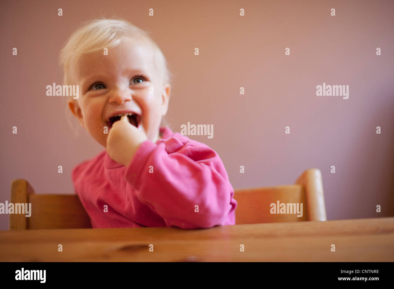 Smiling baby girl sitting at table Stock Photo - Alamy