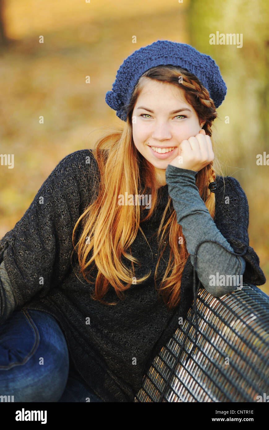 Teenage girl sitting on park bench Stock Photo - Alamy