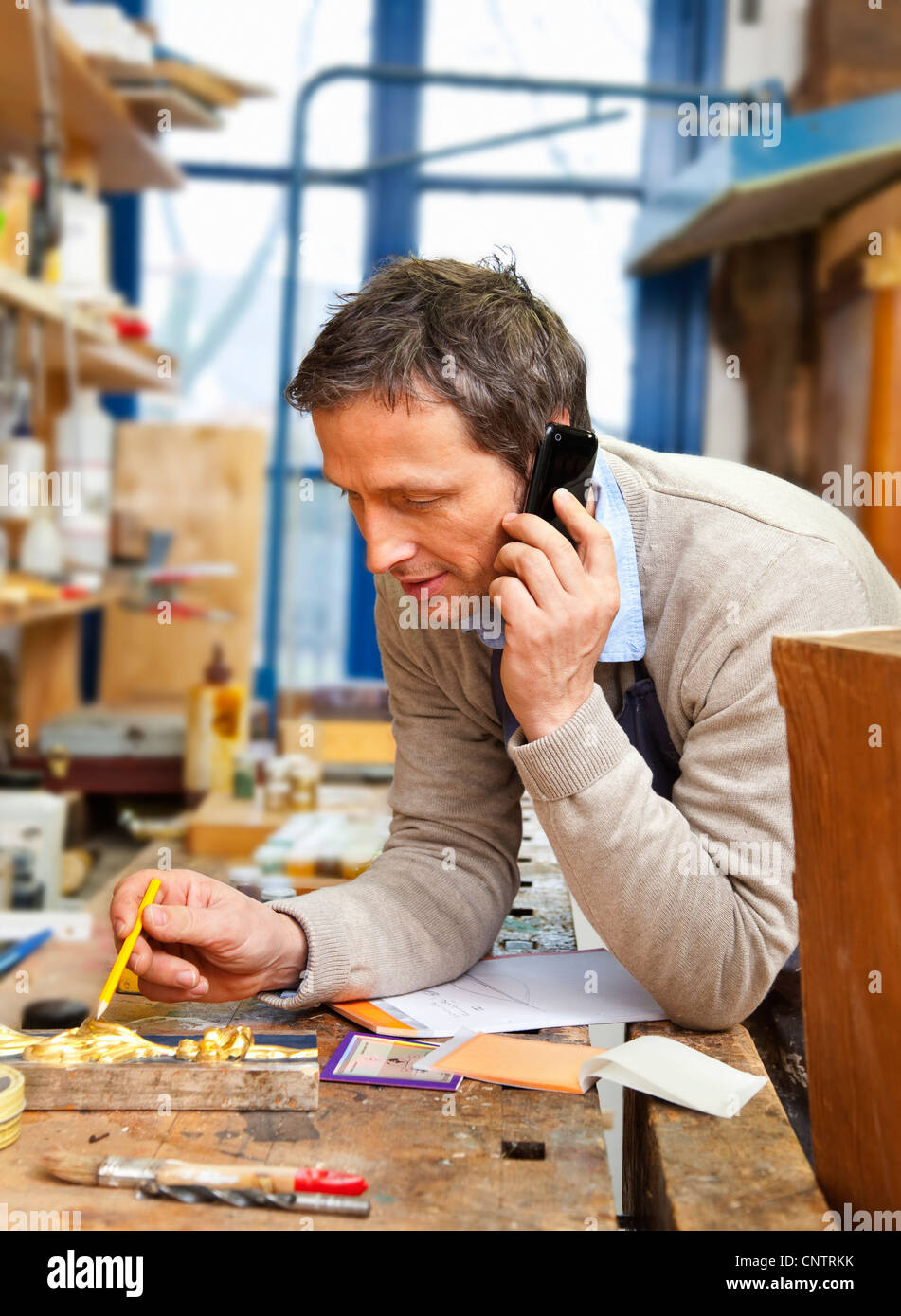 Carpenter talking on phone in shop Stock Photo - Alamy