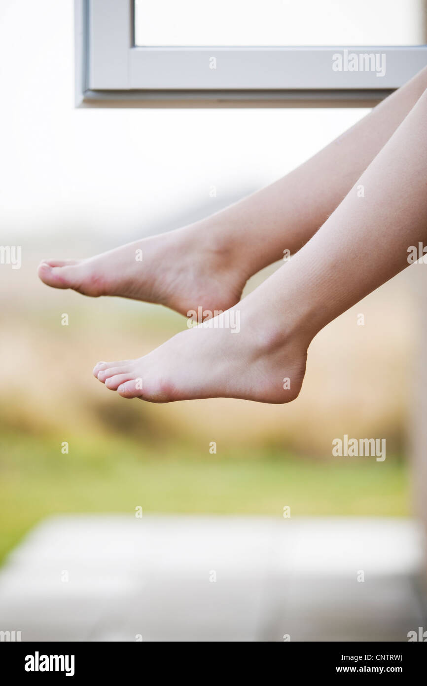 Close up of legs dangling outside window Stock Photo - Alamy