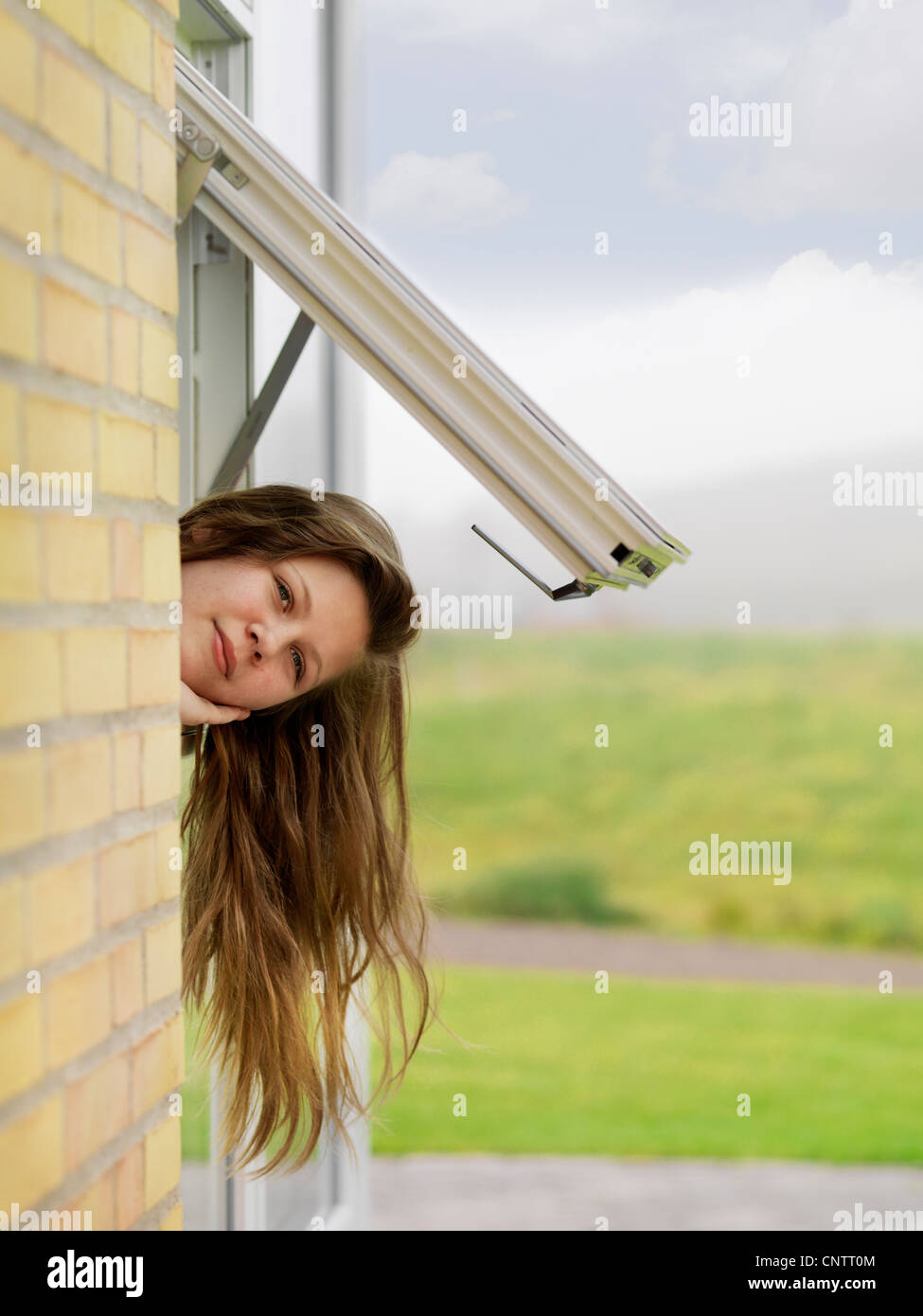 Girl peering outside window Stock Photo - Alamy