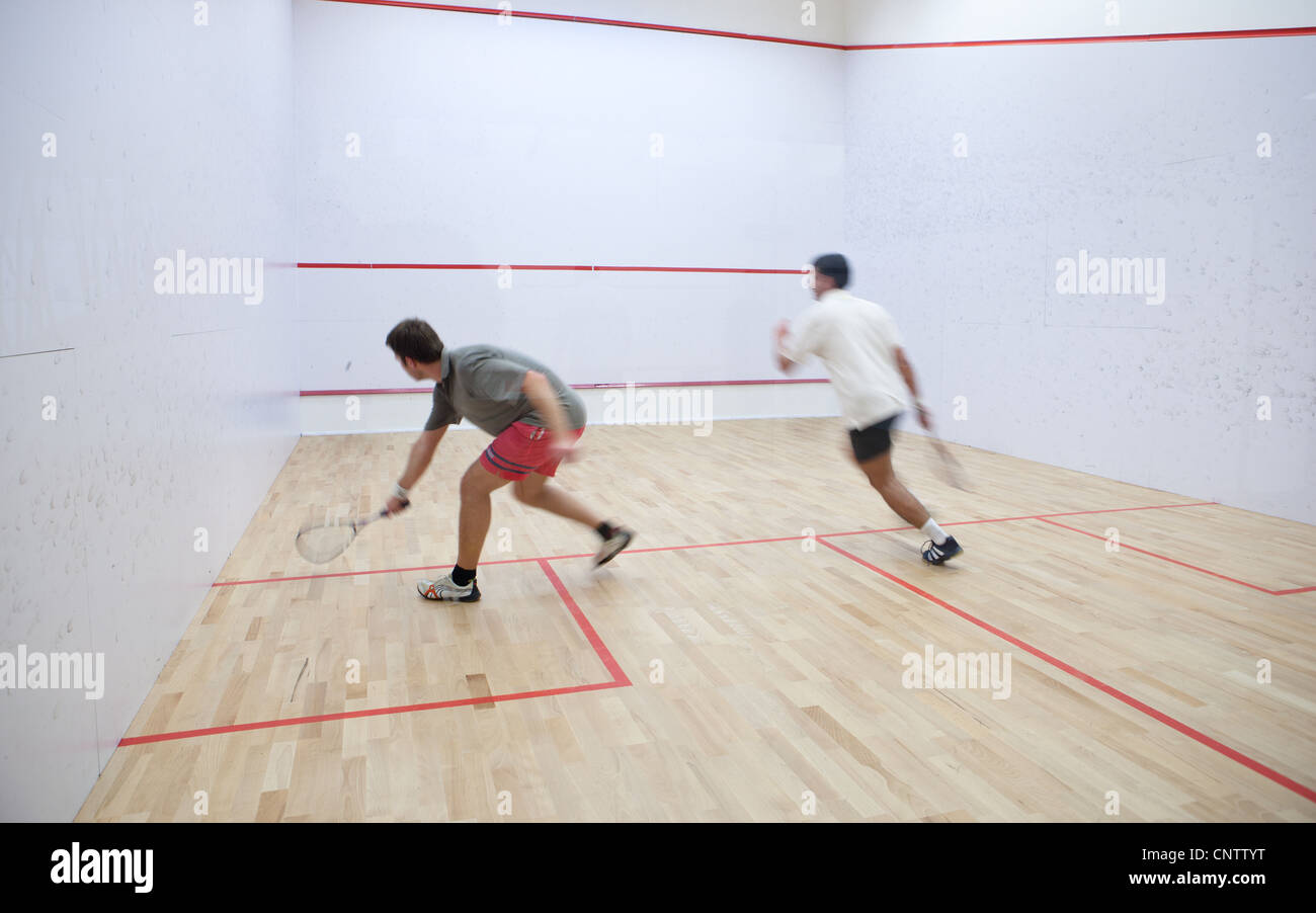 Squash players in action on a squash court (motion blurred image; color ...