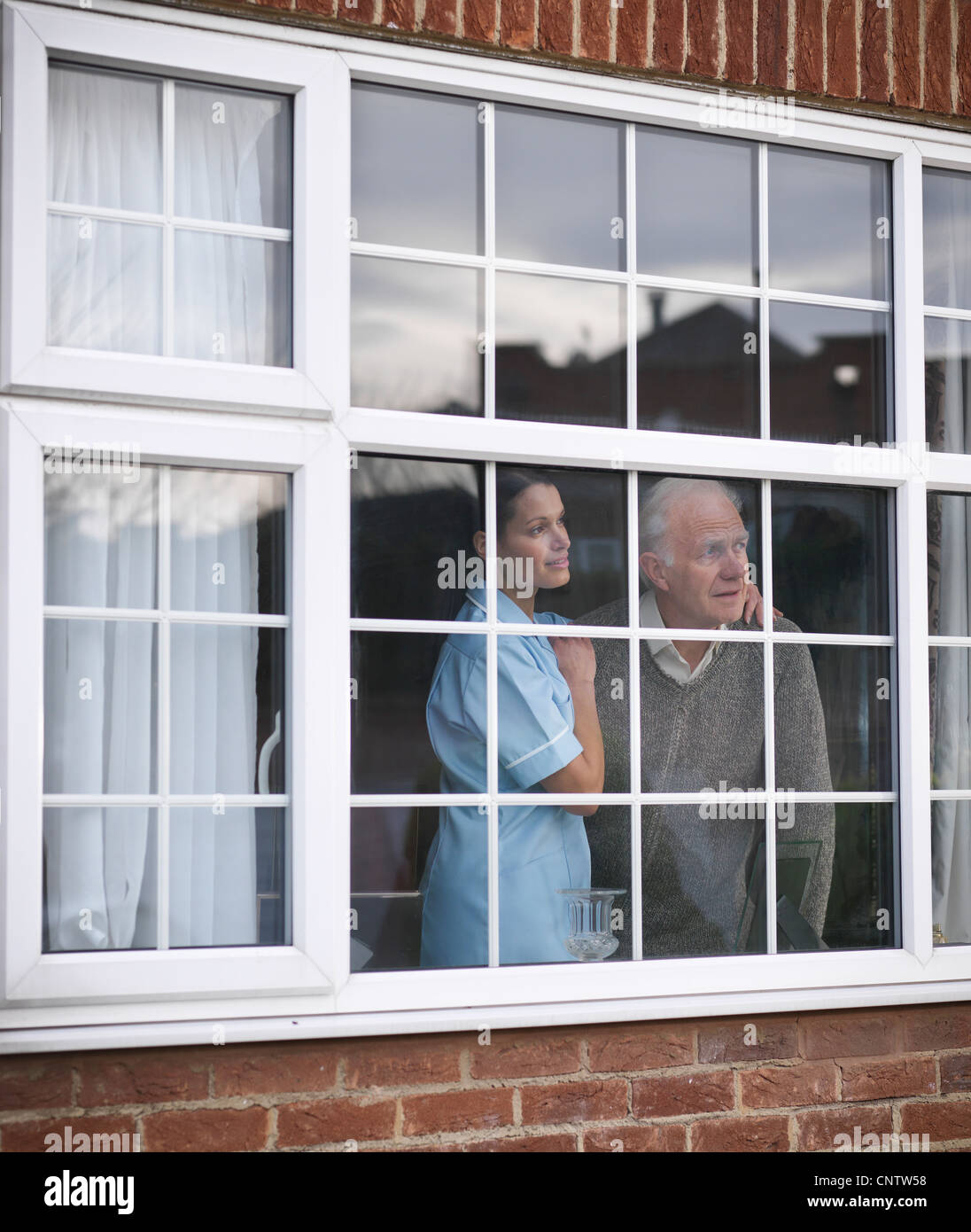 Nurse and older man at window Stock Photo - Alamy