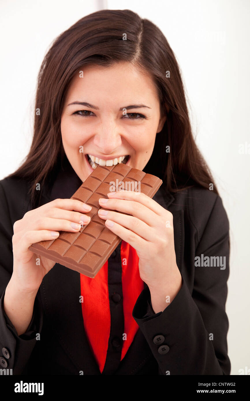 Businesswoman eating bar of chocolate Stock Photo - Alamy