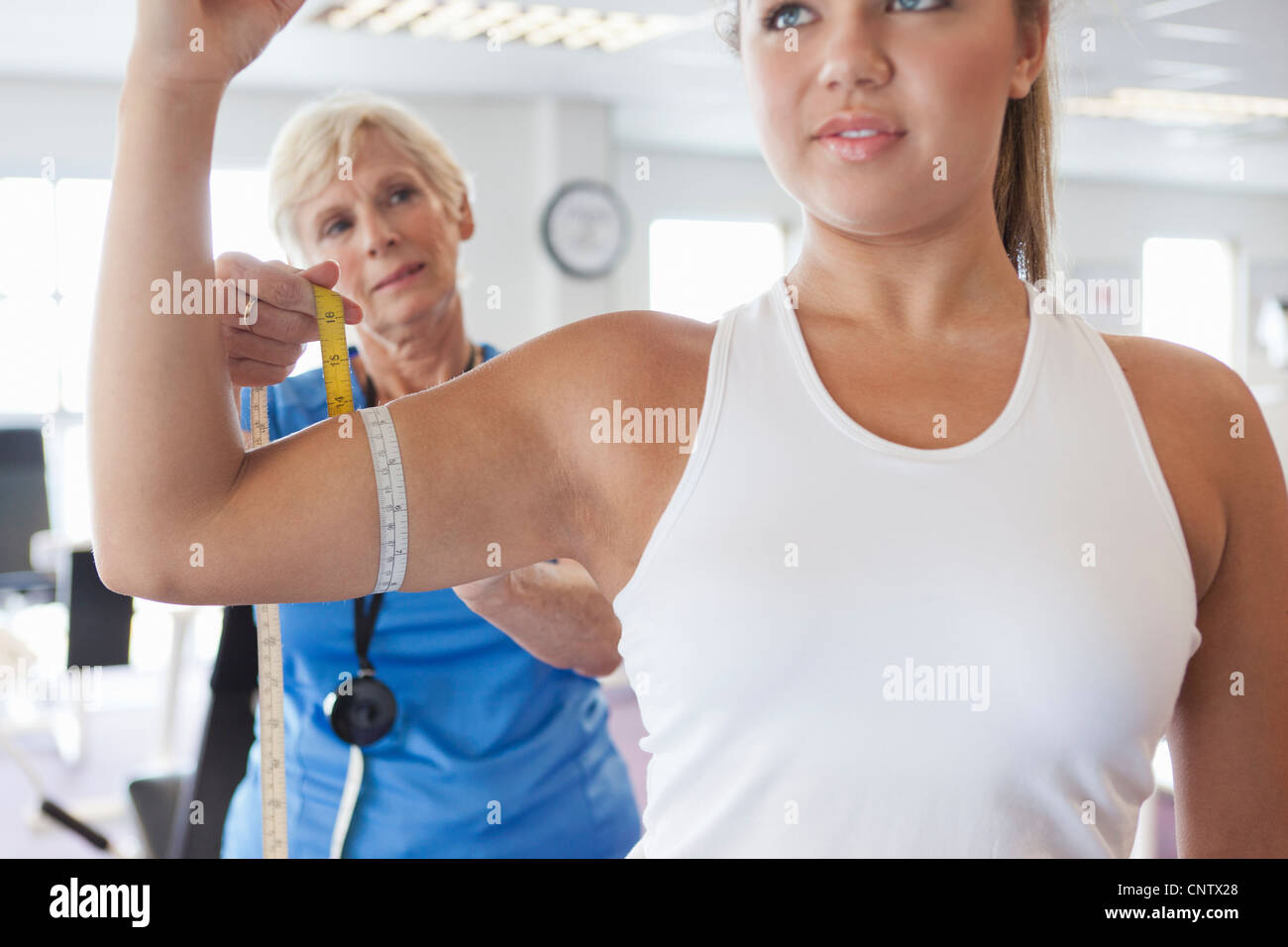 Trainer measuring girls arm in gym Stock Photo - Alamy