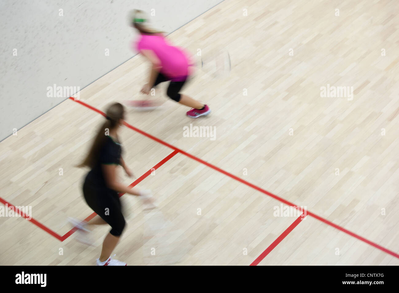 Two female squash players in fast action on a squash court (motion ...