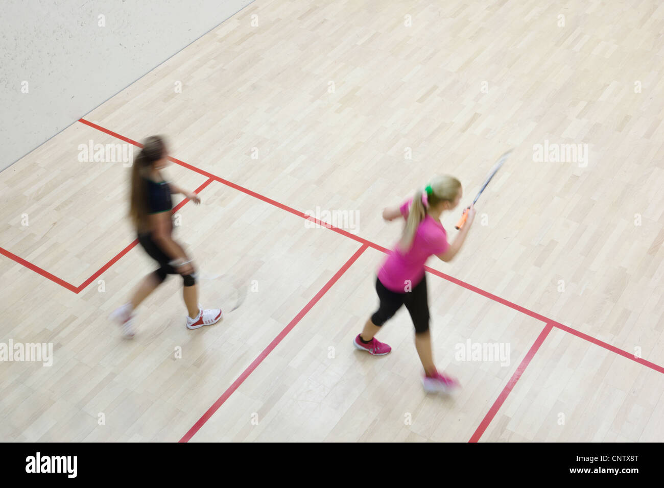 Two female squash players in fast action on a squash court (motion ...
