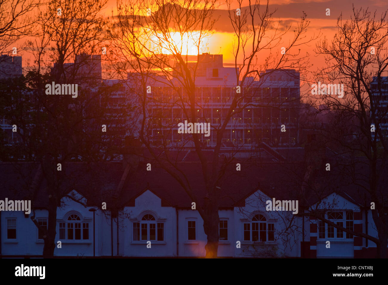 Lens flare from setting sun between layers of cloud over inner-city ...
