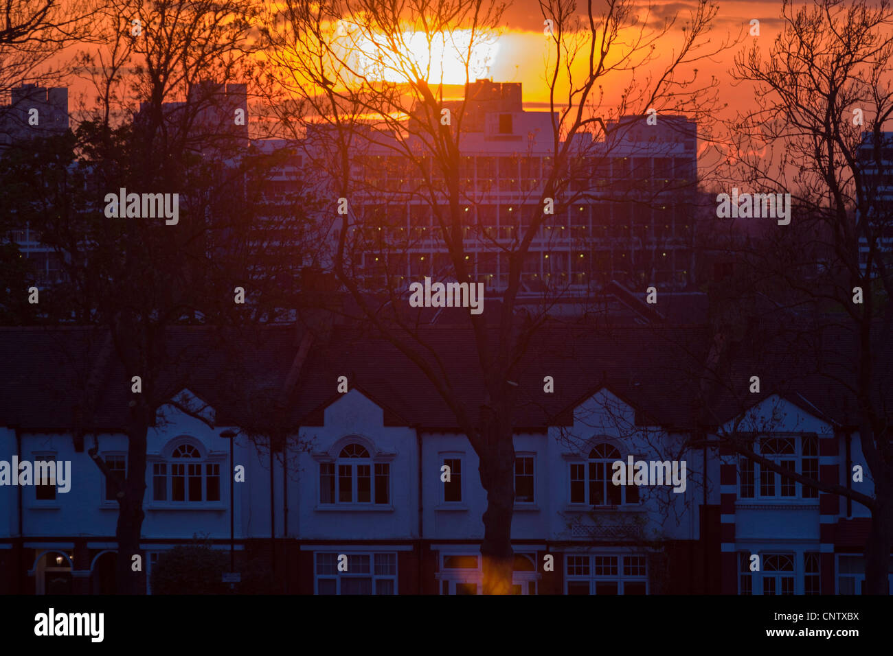 Lens flare from setting sun between layers of cloud over inner-city ...