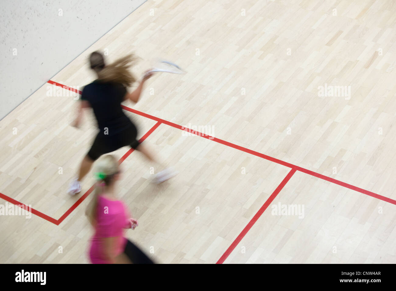 Two female squash players in fast action on a squash court (motion ...